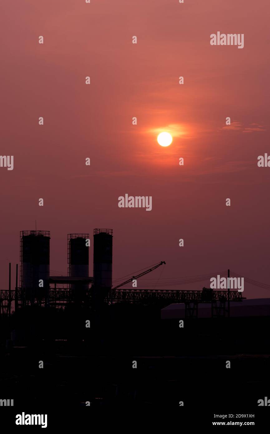 Beautiful sun and the red sky over the silhouette industrial factory ...