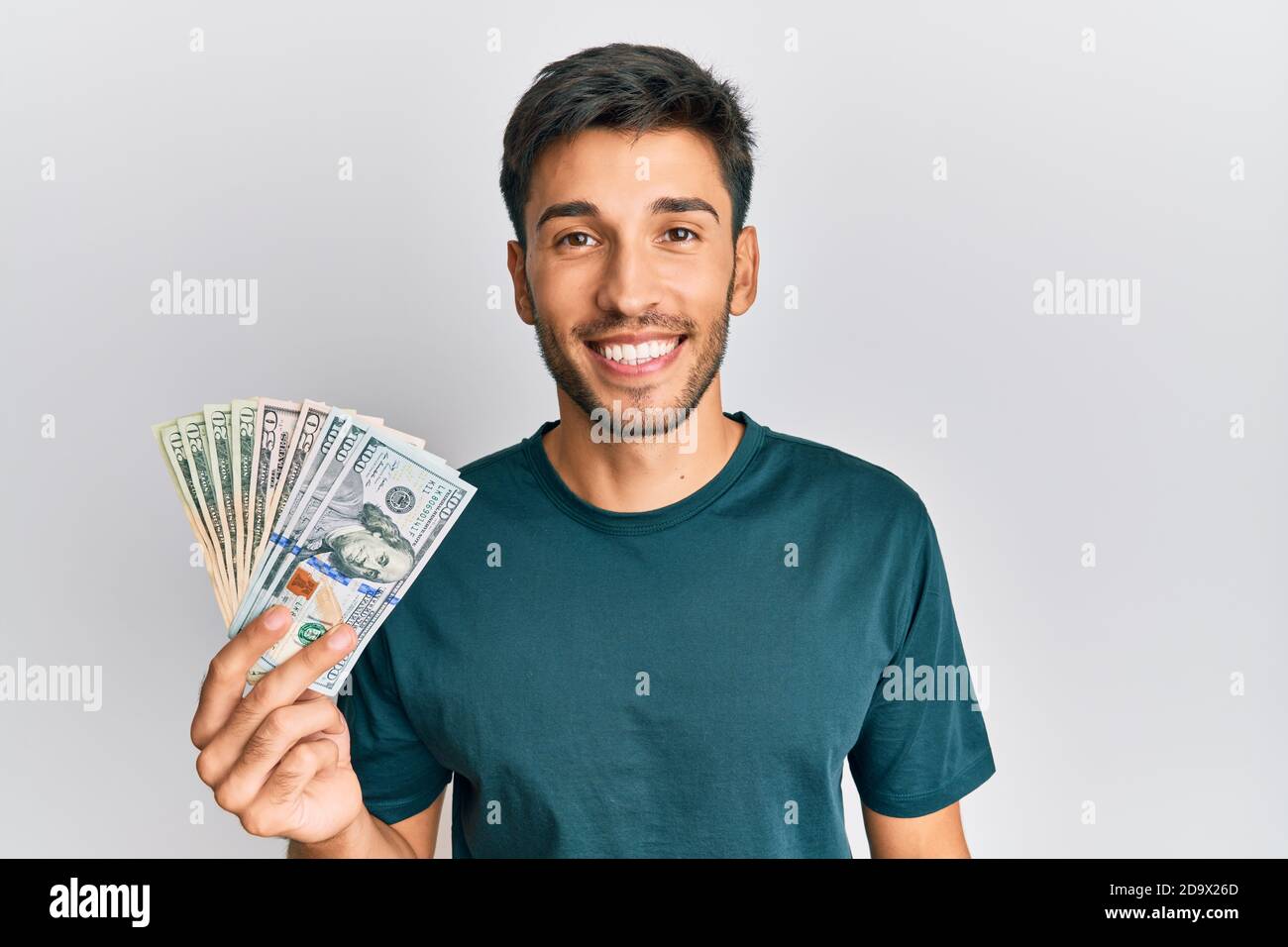 Young handsome man holding dollars looking positive and happy standing ...