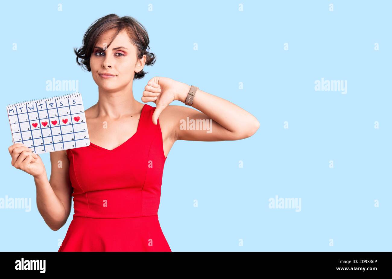 Beautiful young woman with short hair holding heart calendar with angry ...