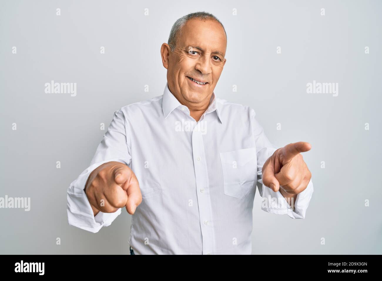 Handsome senior man wearing casual white shirt pointing fingers to ...
