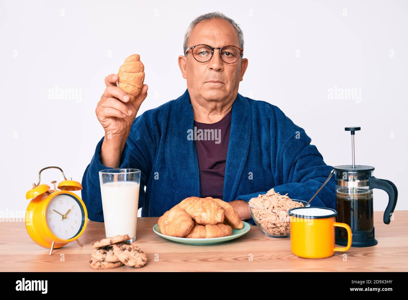 Senior handsome man with gray hair sitting on the table eating ...