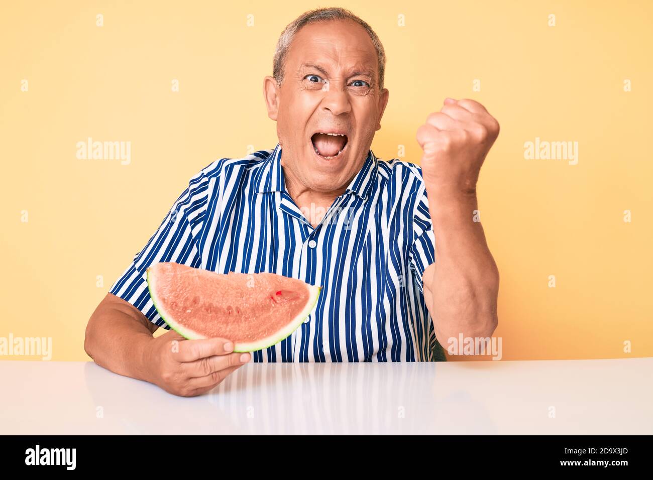 Senior handsome man with gray hair eating sweet watermelon slice ...