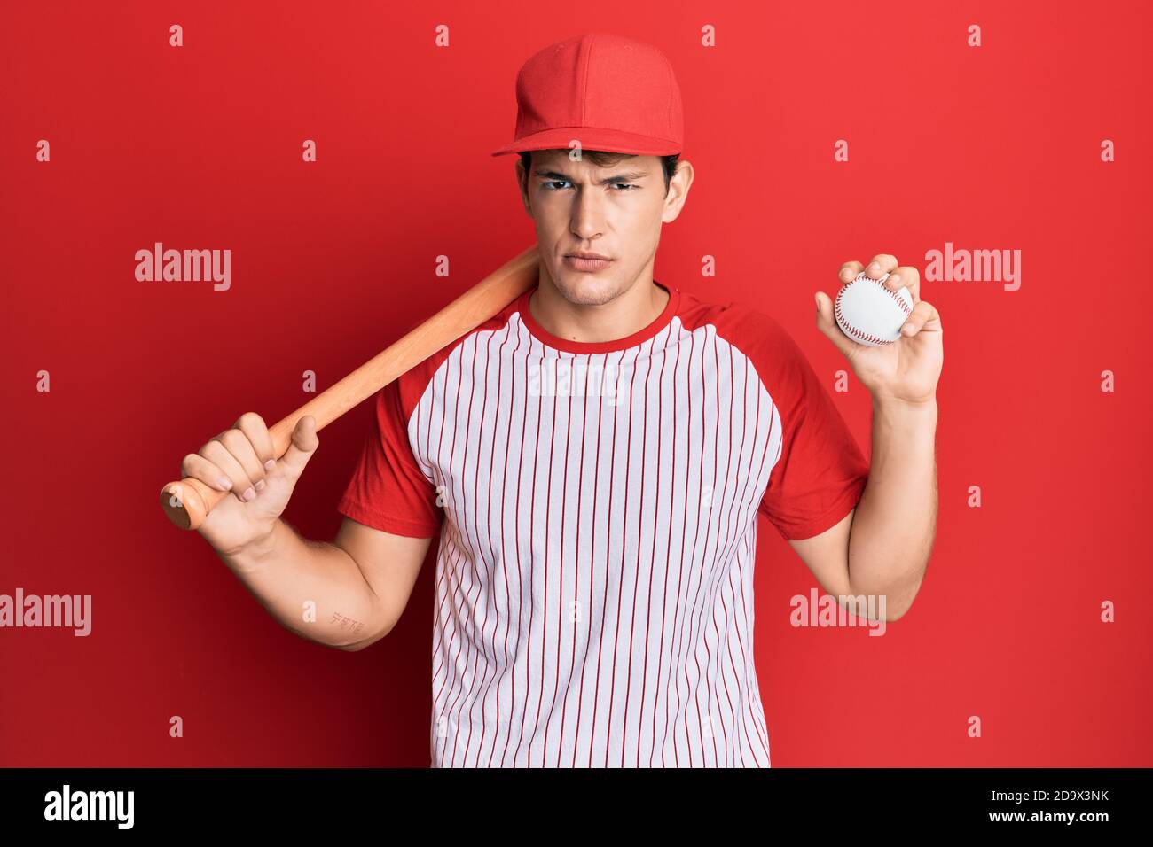 Handsome caucasian man playing baseball holding bat and ball thinking ...