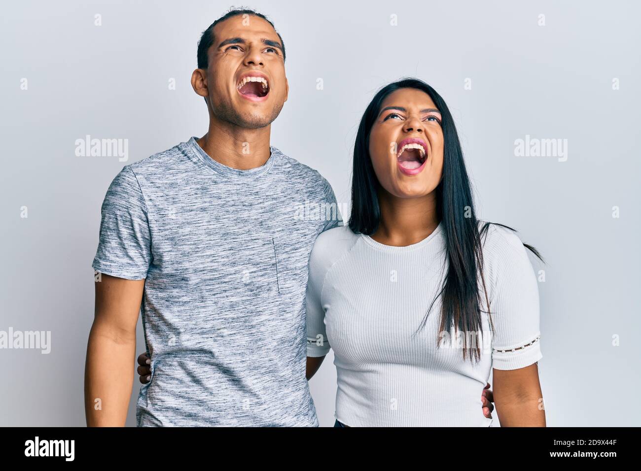 Young latin couple wearing casual clothes angry and mad screaming ...