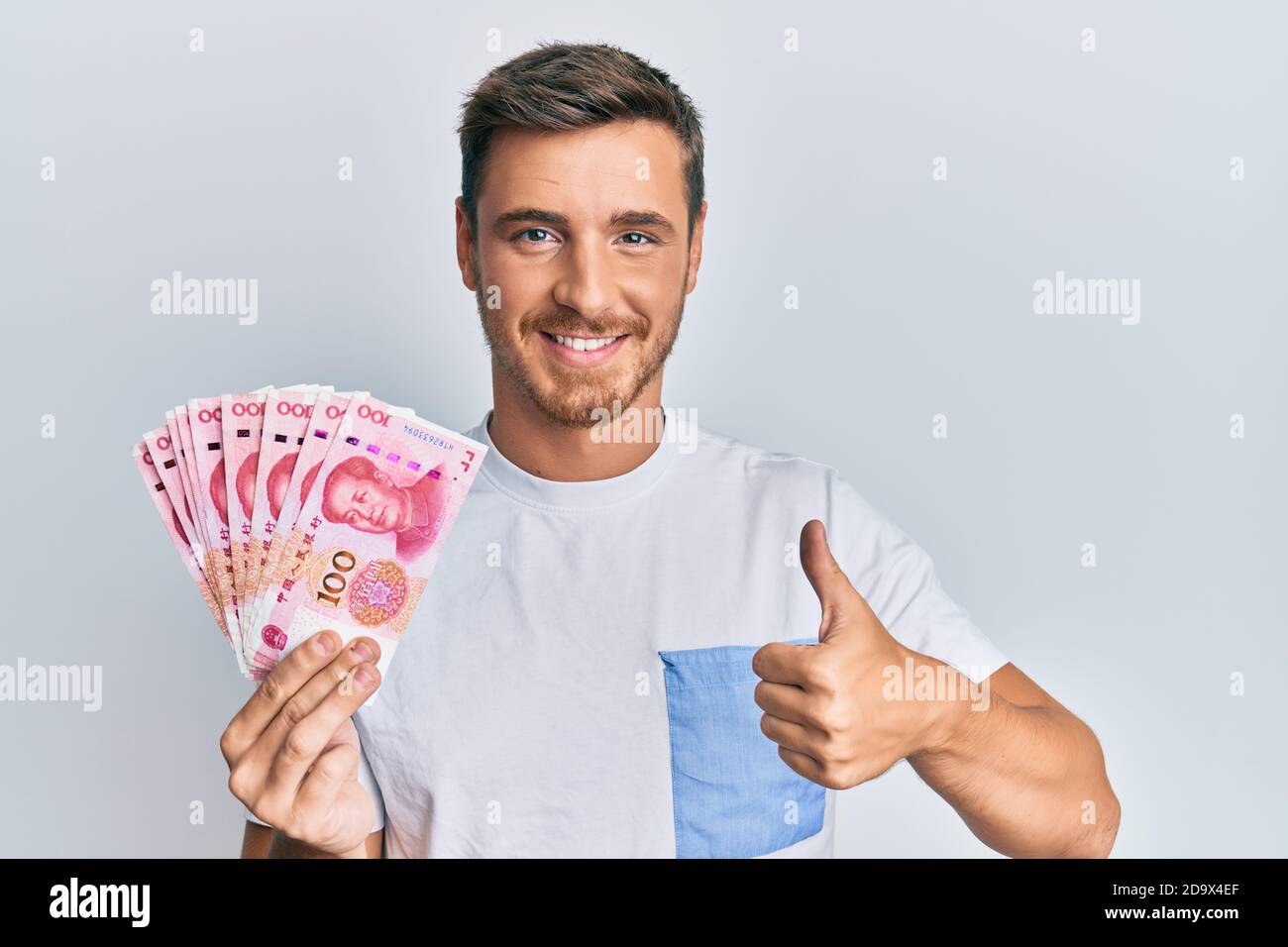 Handsome caucasian man holding 100 yuan chinese banknotes smiling happy ...