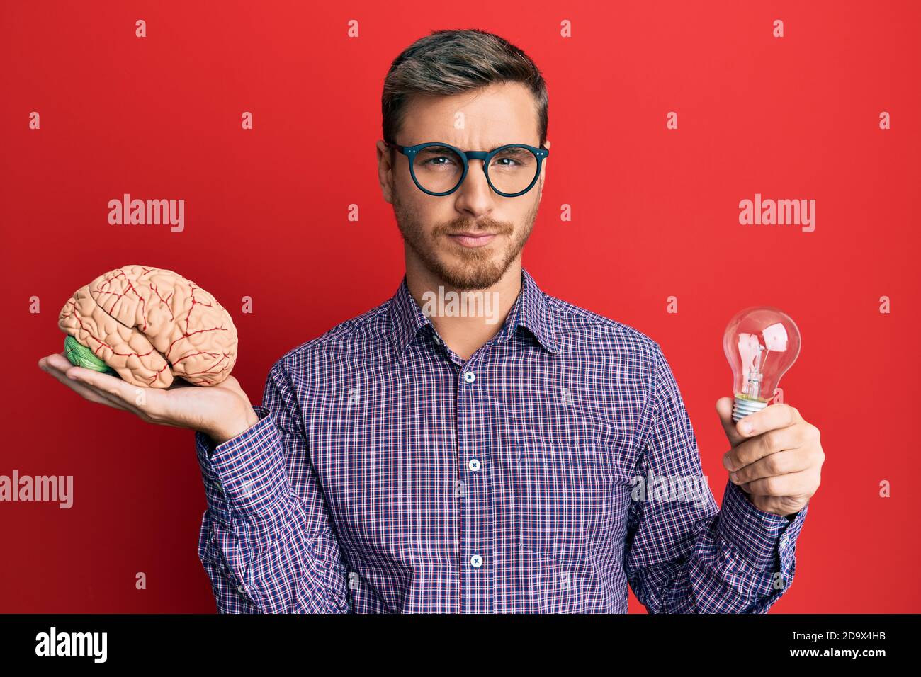 Handsome caucasian man holding brain and lightbulb for inspiration and ...