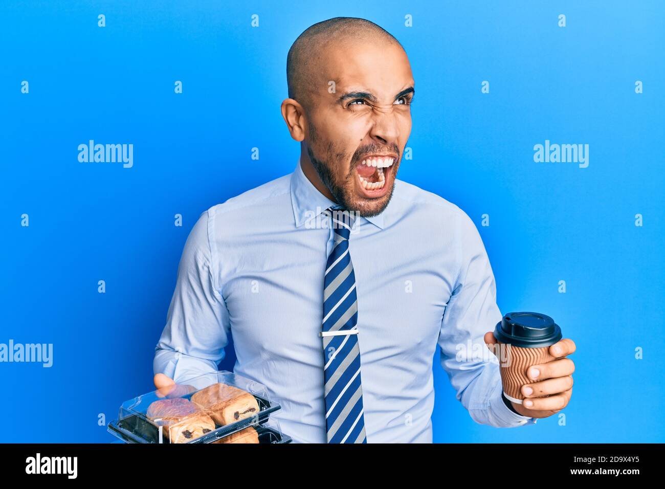 Hispanic adult business man holding take away coffee and sweets angry ...