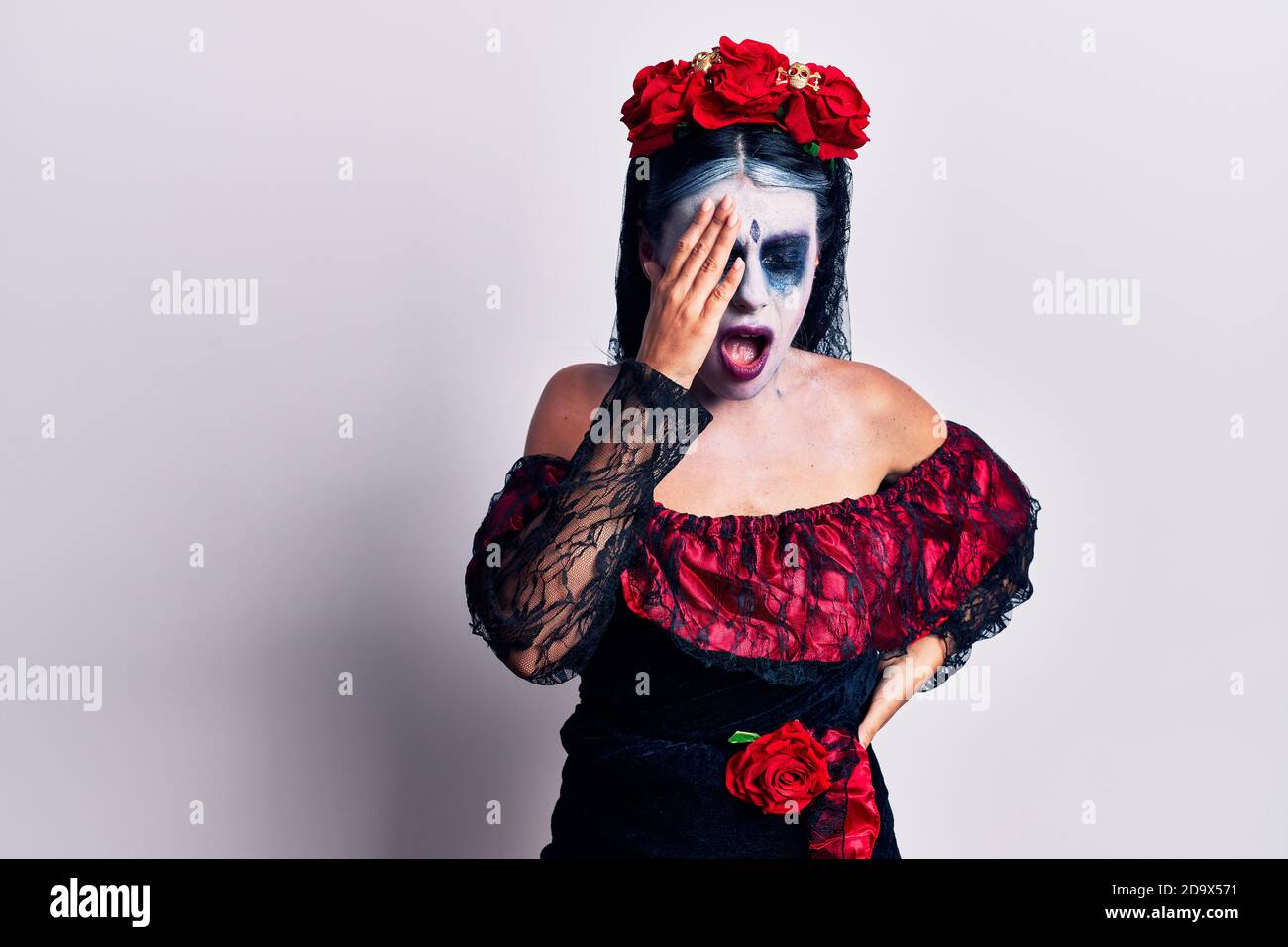 Young woman wearing mexican day of the dead makeup yawning tired ...
