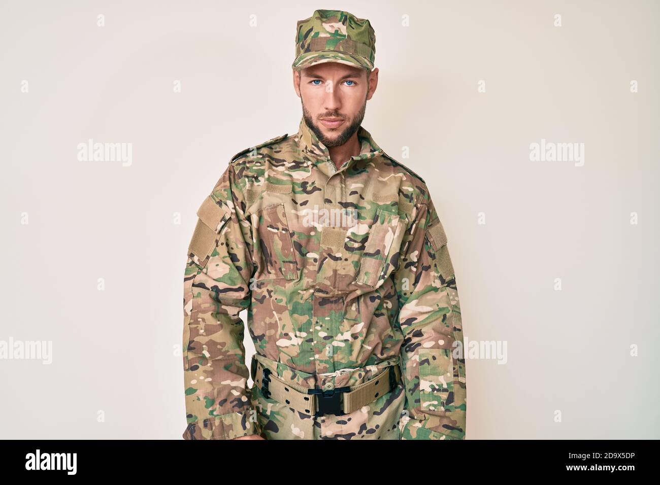 Young caucasian man wearing camouflage army uniform looking sleepy and ...