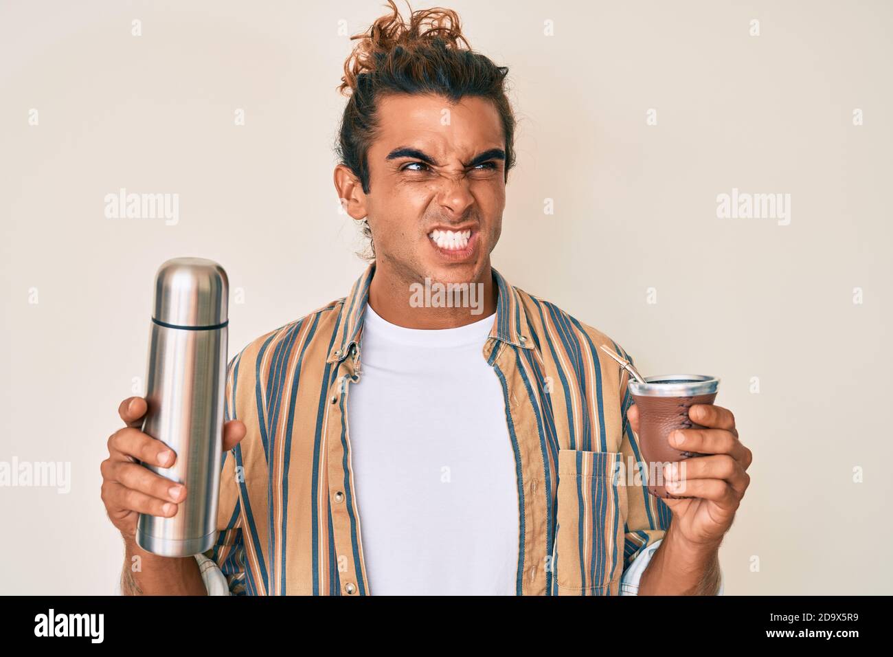Young hispanic man drinking mate infusion angry and mad screaming ...