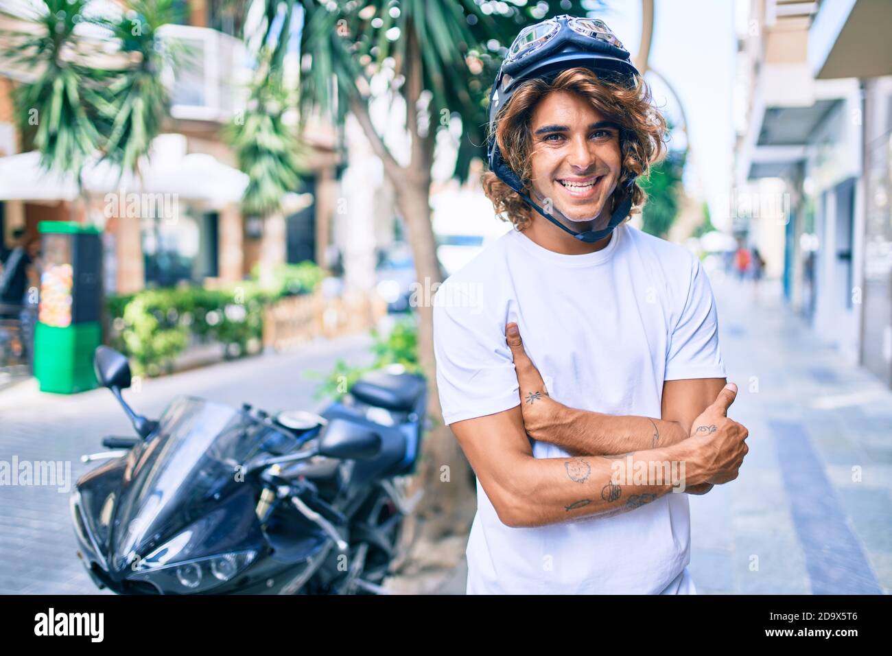 Young hispanic man smiling happy wearing moto helmet over motorcycle at ...