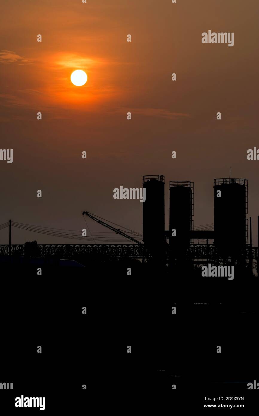 Beautiful sun and the red sky over the silhouette industrial factory ...