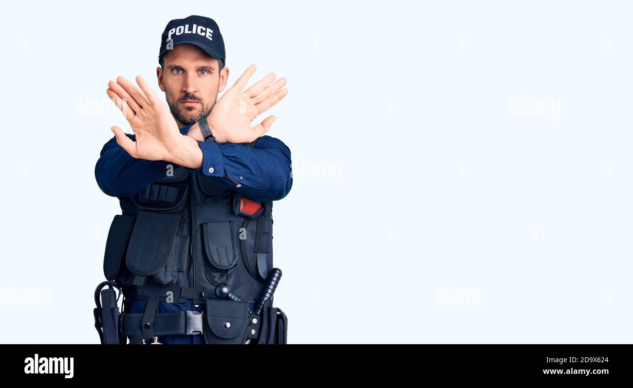 Young handsome man wearing police uniform rejection expression crossing ...