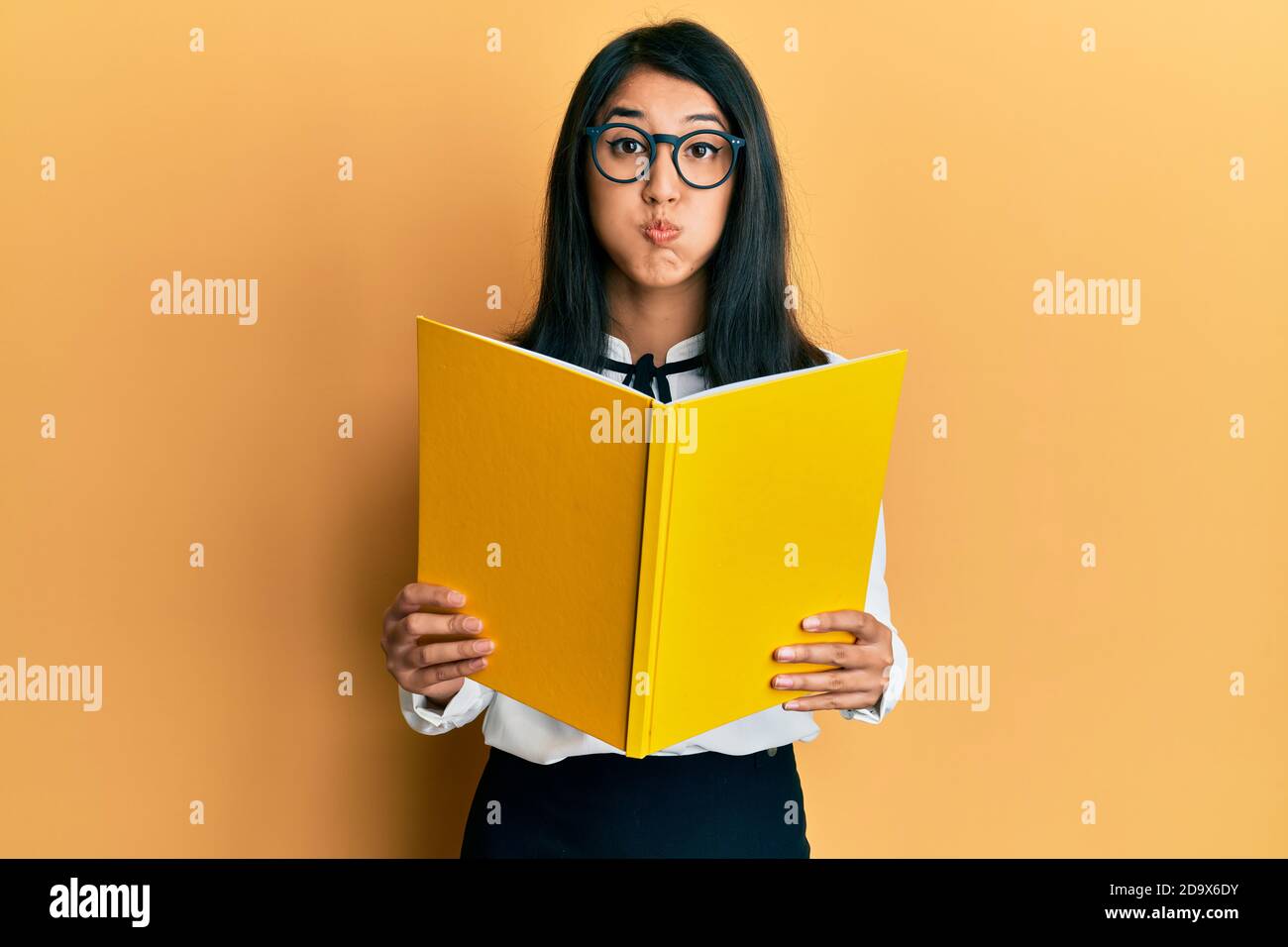 Beautiful asian young woman reading a book wearing glasses puffing ...
