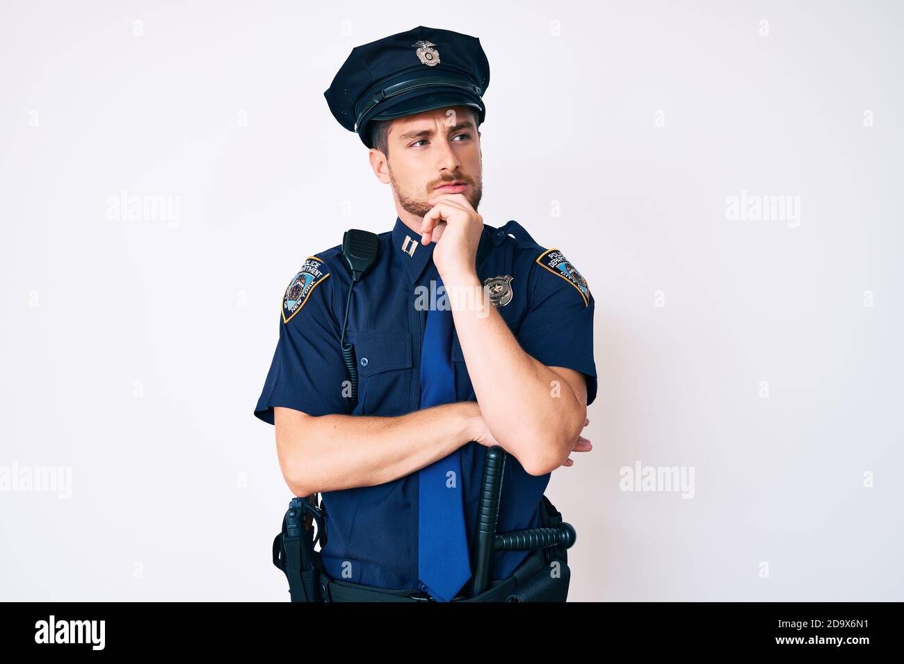 Young caucasian man wearing police uniform with hand on chin thinking ...