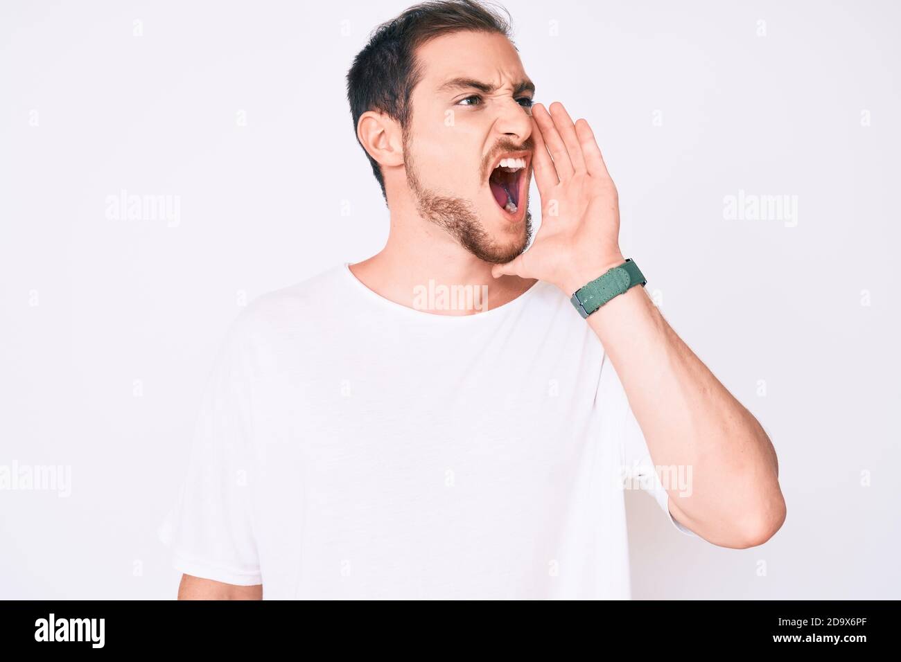 Young handsome man wearing casual white tshirt shouting and screaming ...
