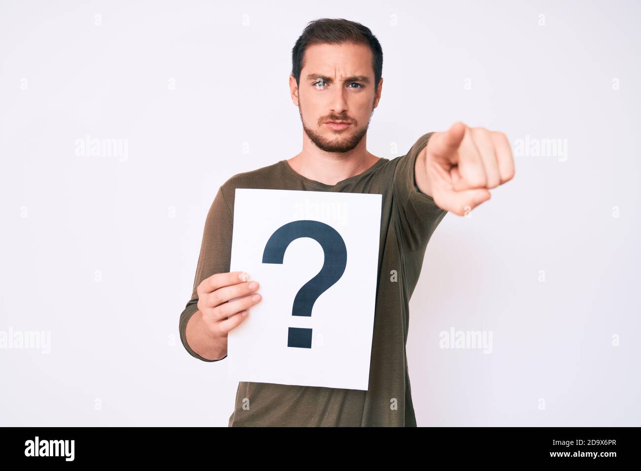 Young handsome man holding question mark pointing with finger to the ...