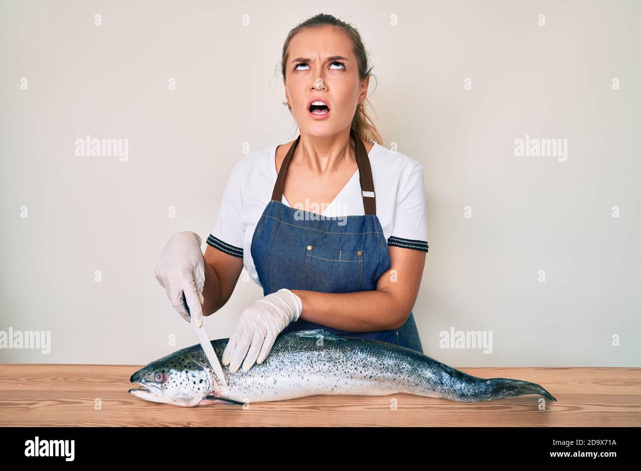 Beautiful caucasian woman fishmonger selling fresh raw salmon angry and ...