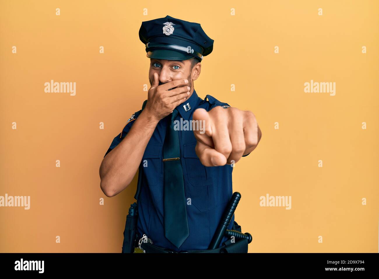 Handsome hispanic man wearing police uniform laughing at you, pointing ...