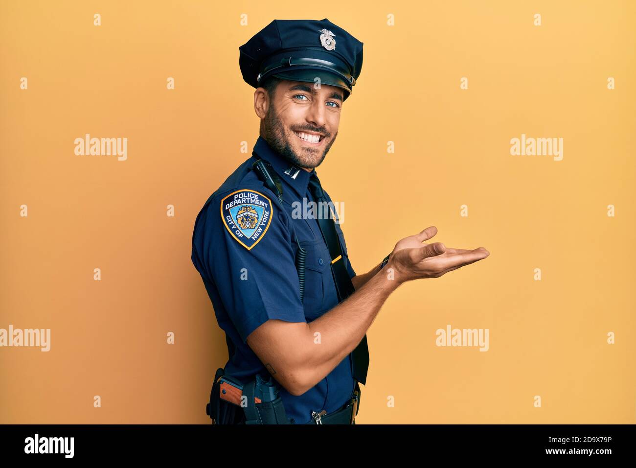 Handsome hispanic man wearing police uniform pointing aside with hands ...