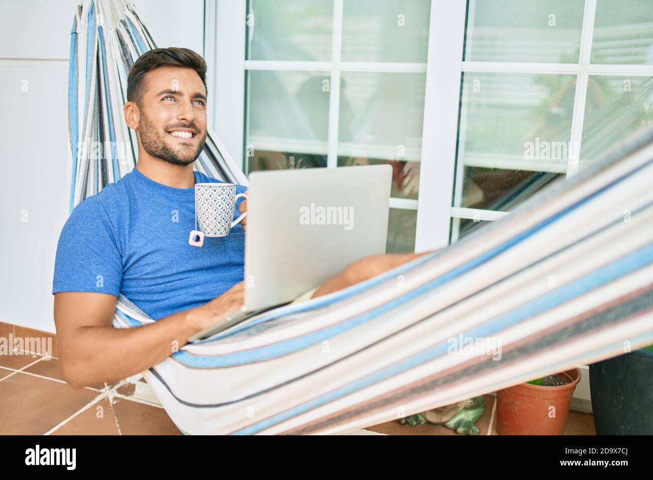 Young hispanic man relaxed working using laptop and drinking coffee ...
