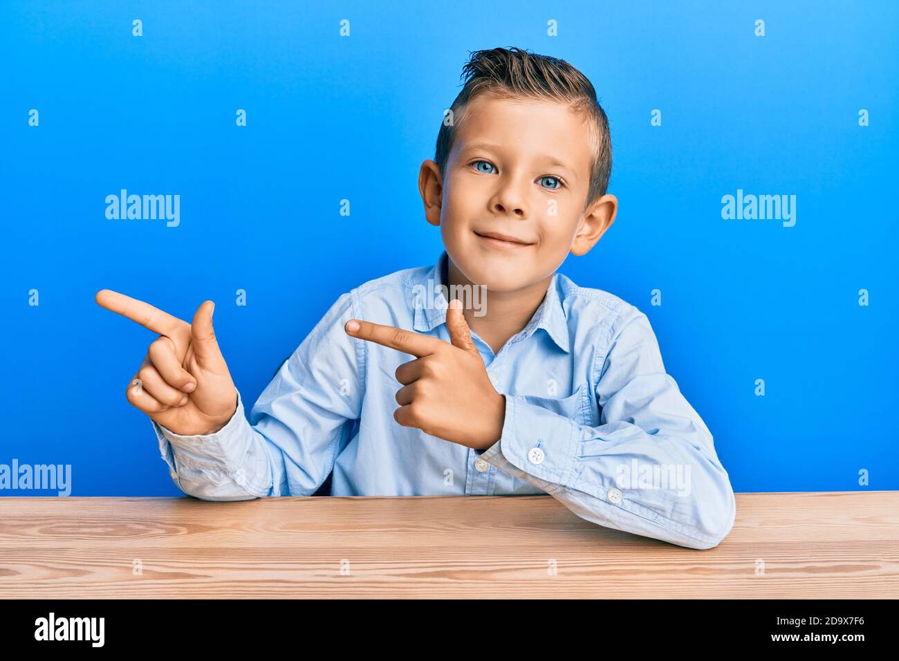 Adorable caucasian kid wearing casual clothes sitting on the table ...