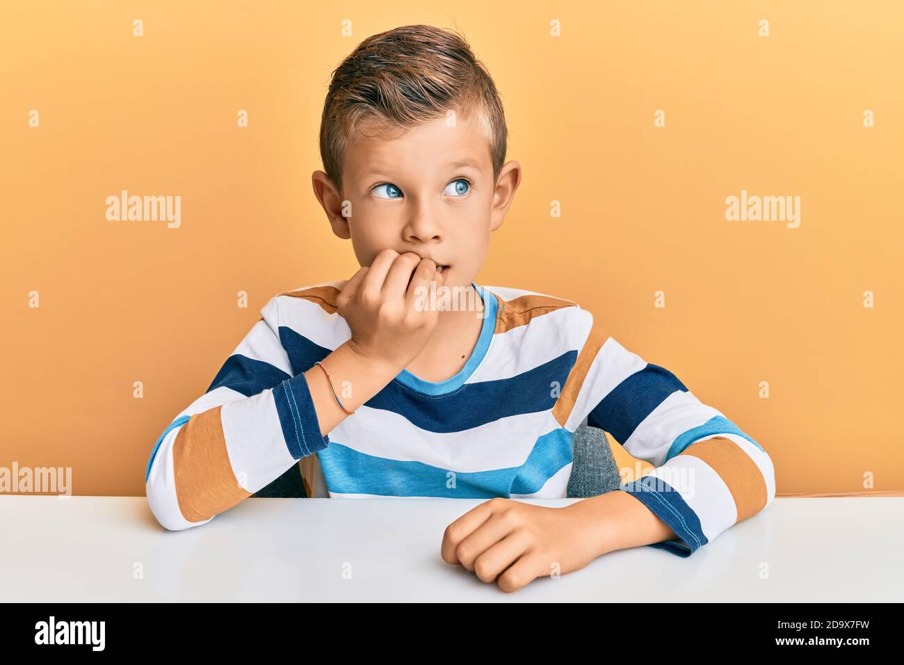 Adorable caucasian kid wearing casual clothes sitting on the table ...