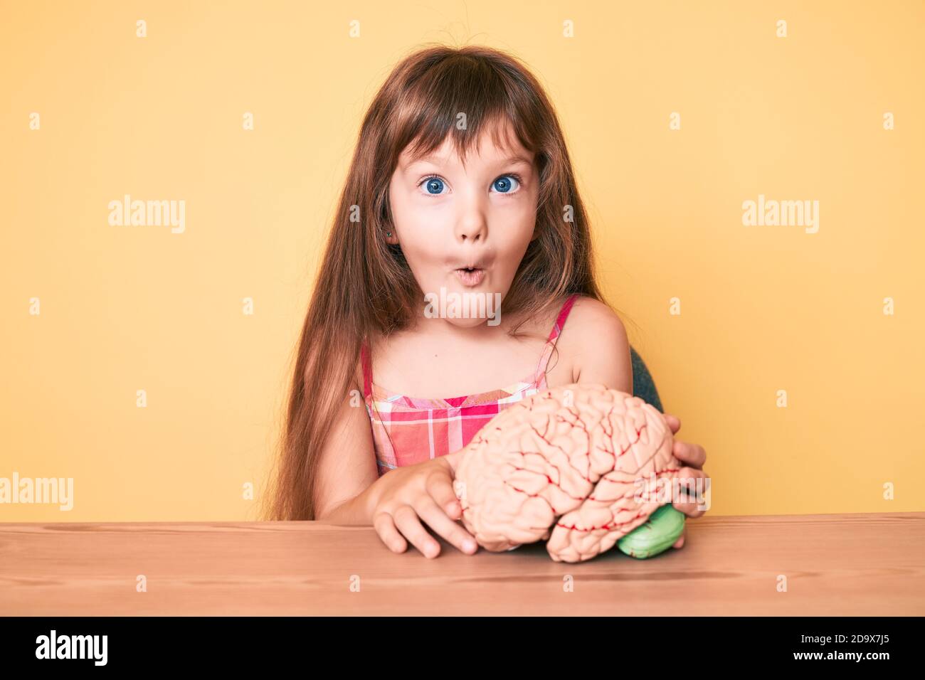 Little caucasian kid girl with long hair holding brain as mental health ...