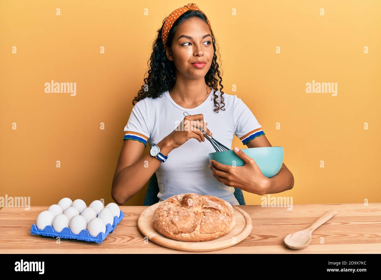 Young african american girl making homemade bread sitting on the table ...