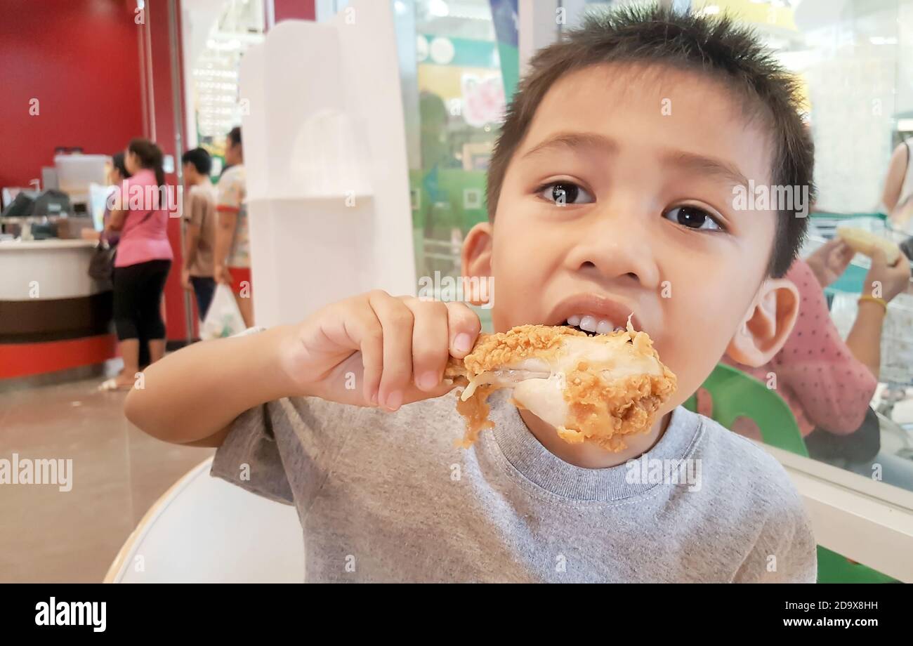 Cute Asian boy eating fried chicken is delicious Stock Photo - Alamy