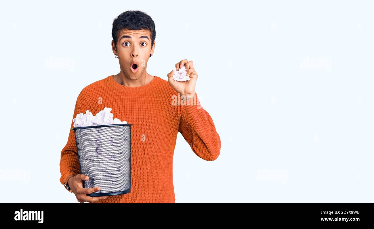 Young african amercian man holding paper bin full of crumpled papers ...
