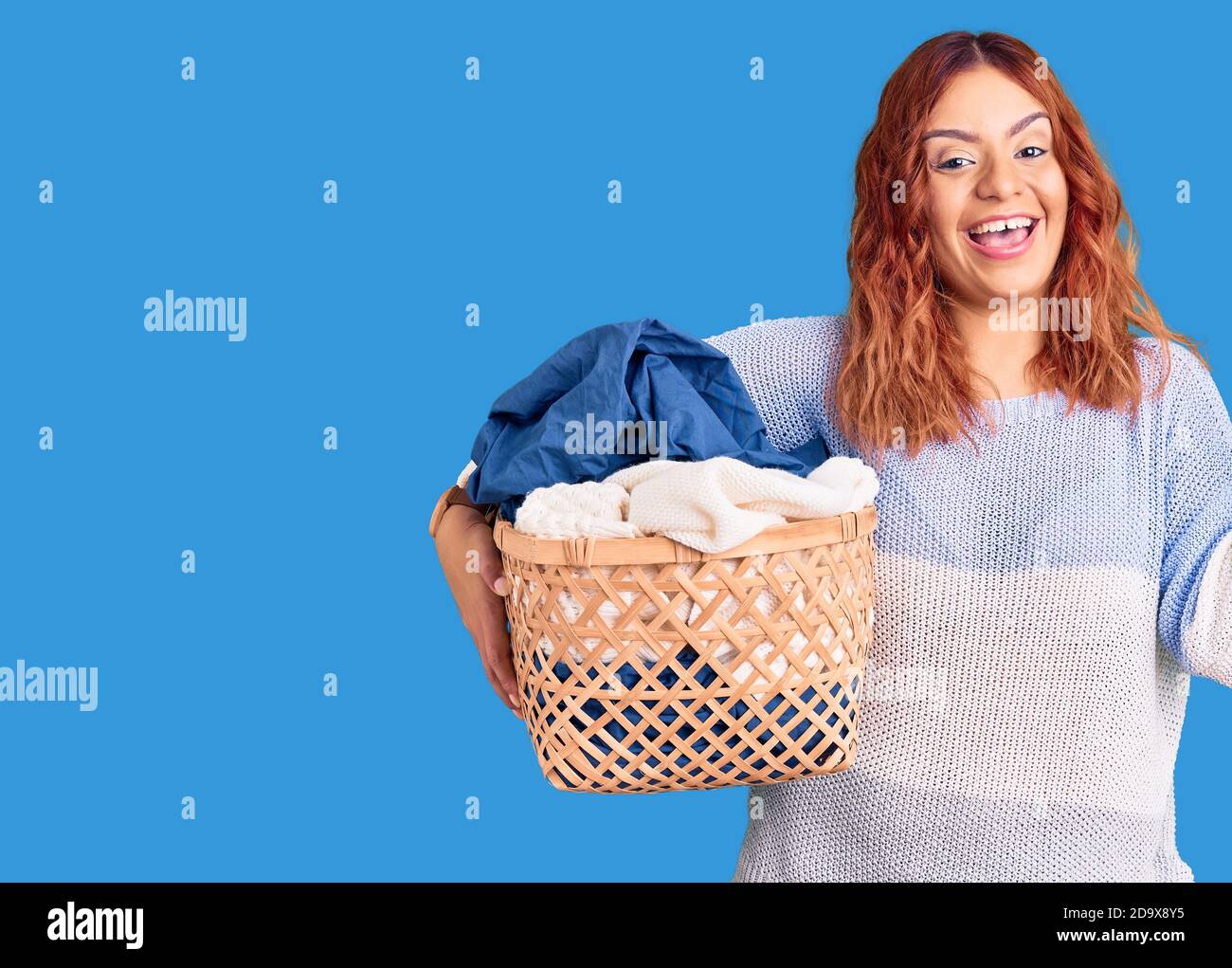 Young latin woman holding laundry basket screaming proud, celebrating ...