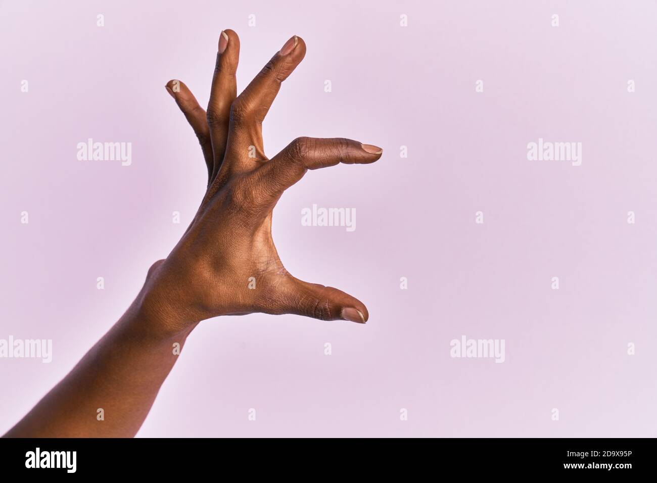 Arm and hand of black middle age woman over pink isolated background ...