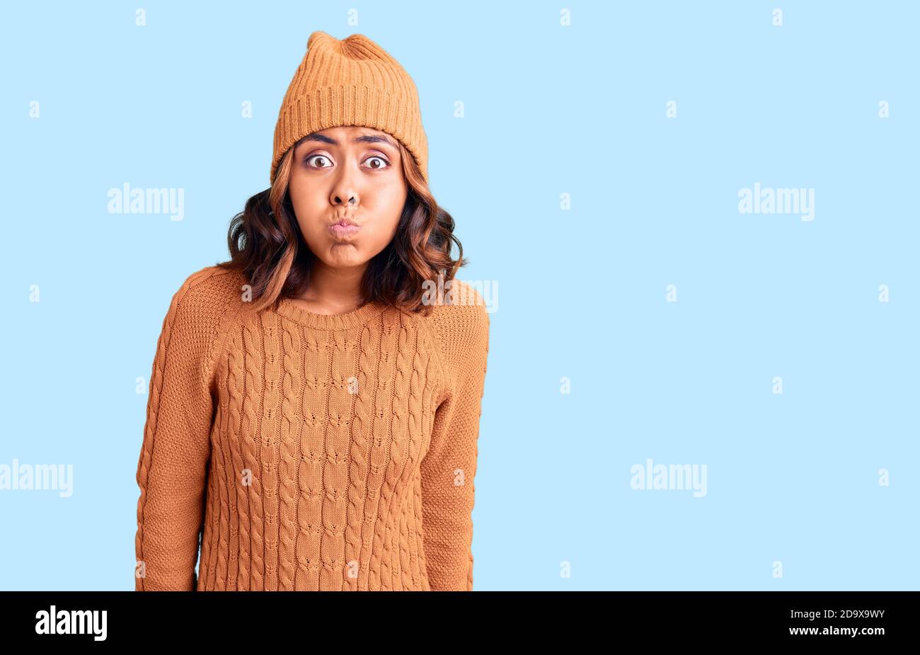 Young beautiful mixed race woman wearing wool sweater and winter hat ...