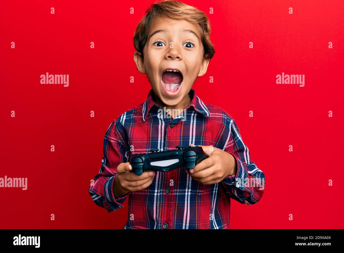Adorable latin kid playing video game holding controller celebrating ...