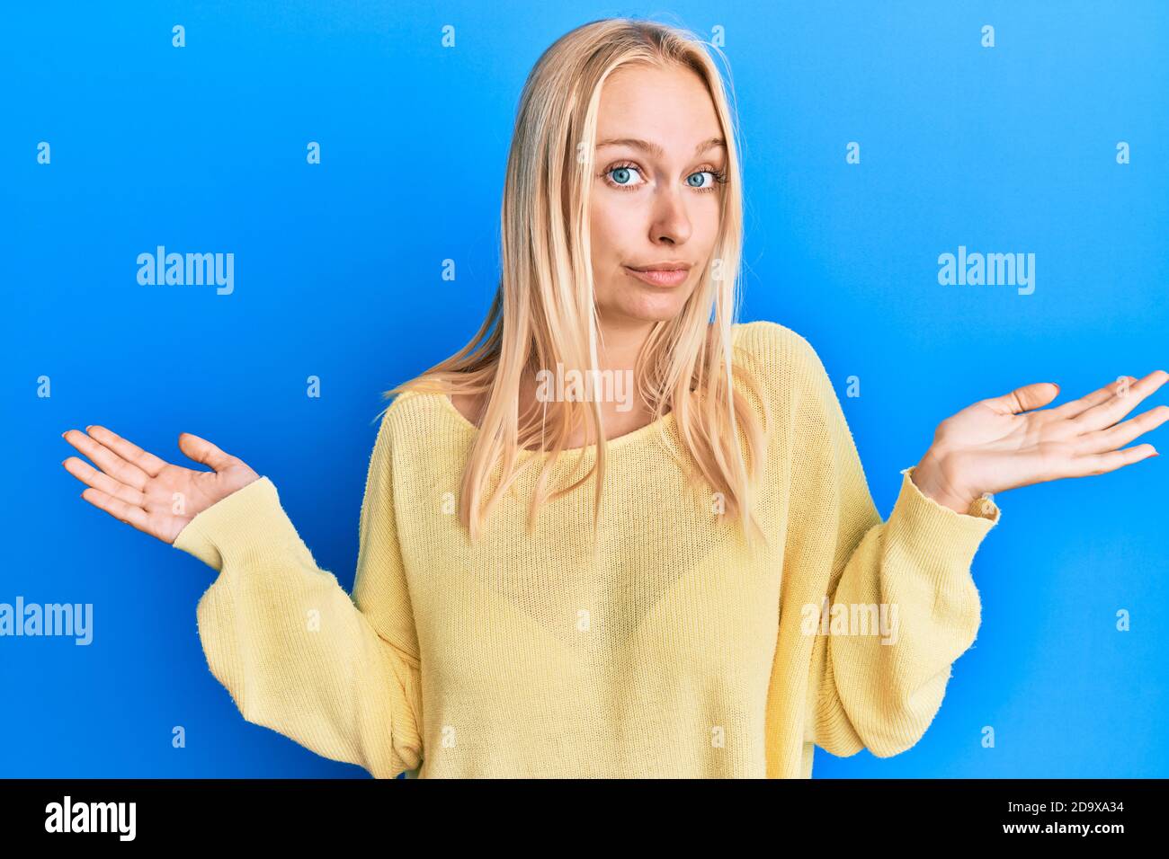 Young blonde girl wearing casual clothes clueless and confused with ...
