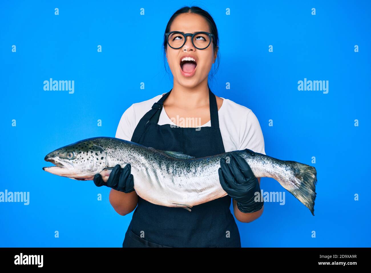 Young beautiful asian girl fishmonger selling fresh raw salmon angry ...
