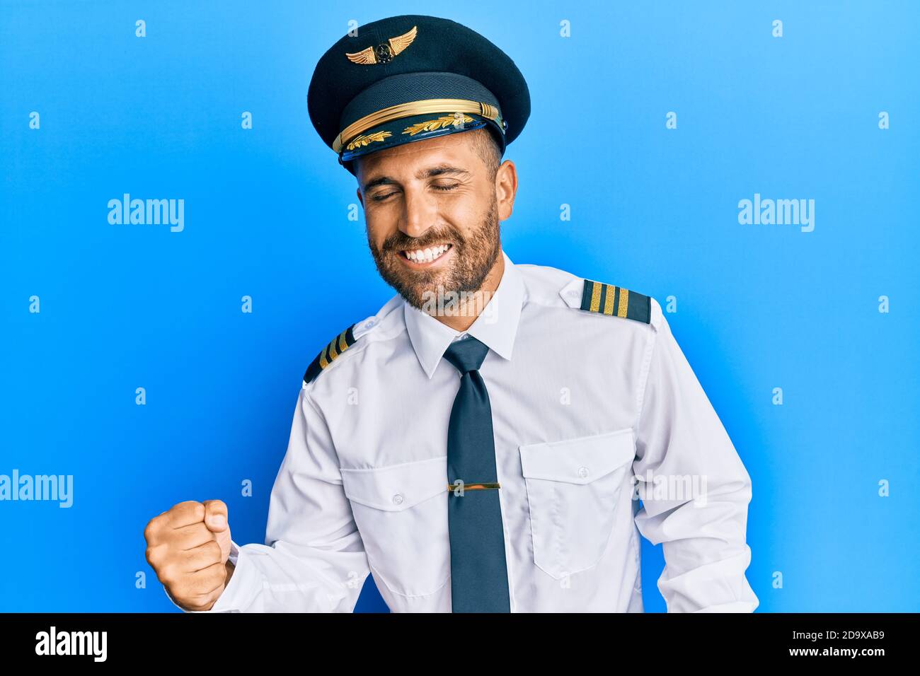 Handsome man with beard wearing airplane pilot uniform very happy and ...