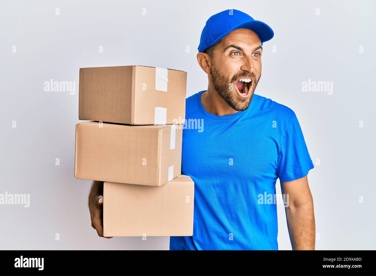 Handsome man with beard wearing courier uniform holding delivery ...