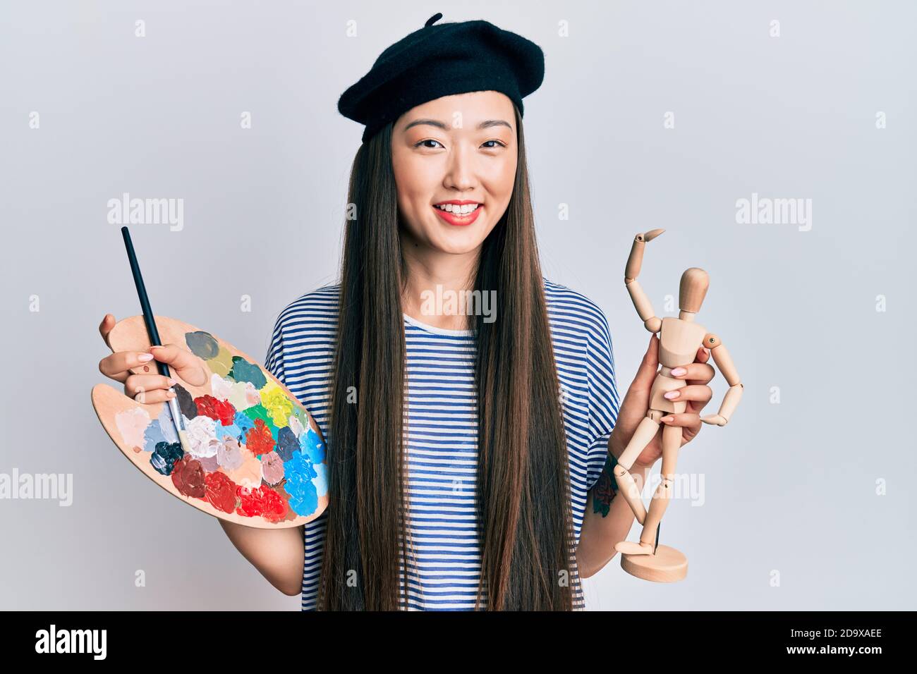 Young chinese woman wearing artist look with beret holding manikin ...