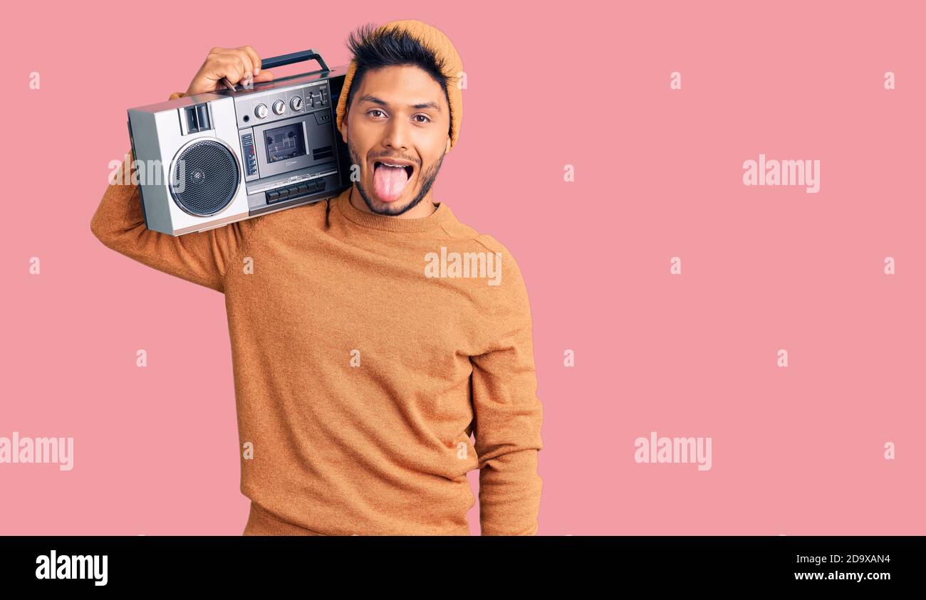 Handsome latin american young man holding boombox, listening to music ...