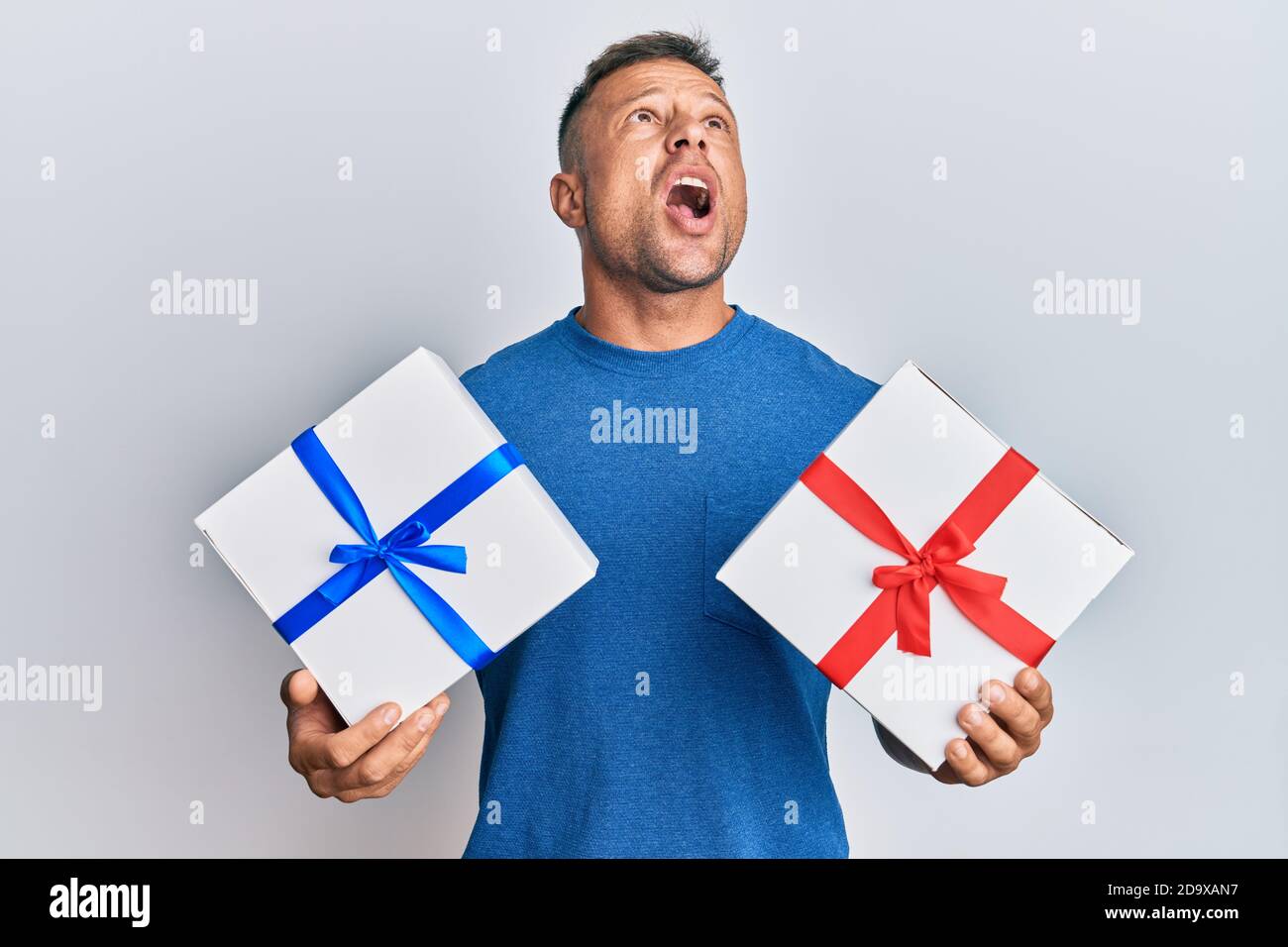 Handsome muscle man holding gifts angry and mad screaming frustrated ...