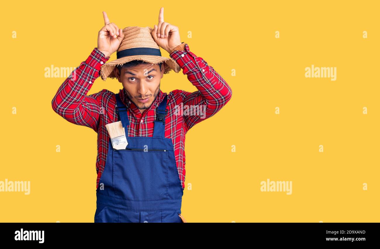 Handsome latin american young man weaing handyman uniform doing funny ...