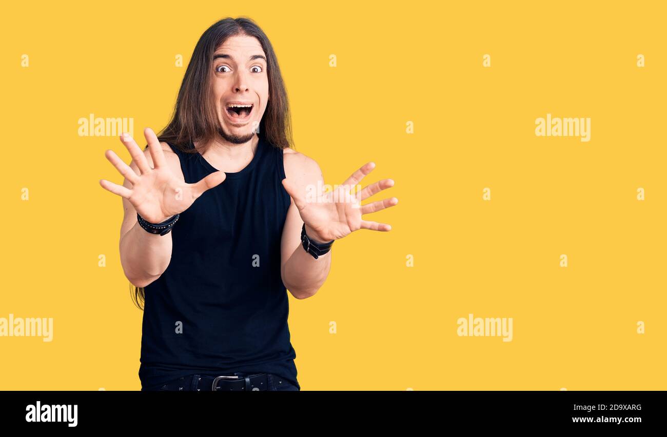 Young adult man with long hair wearing goth style with black clothes ...