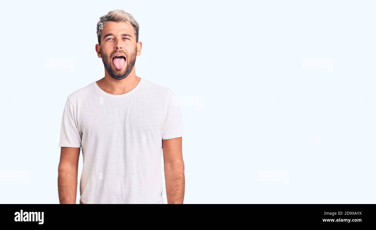 Young handsome blond man wearing casual t-shirt with hand on stomach ...