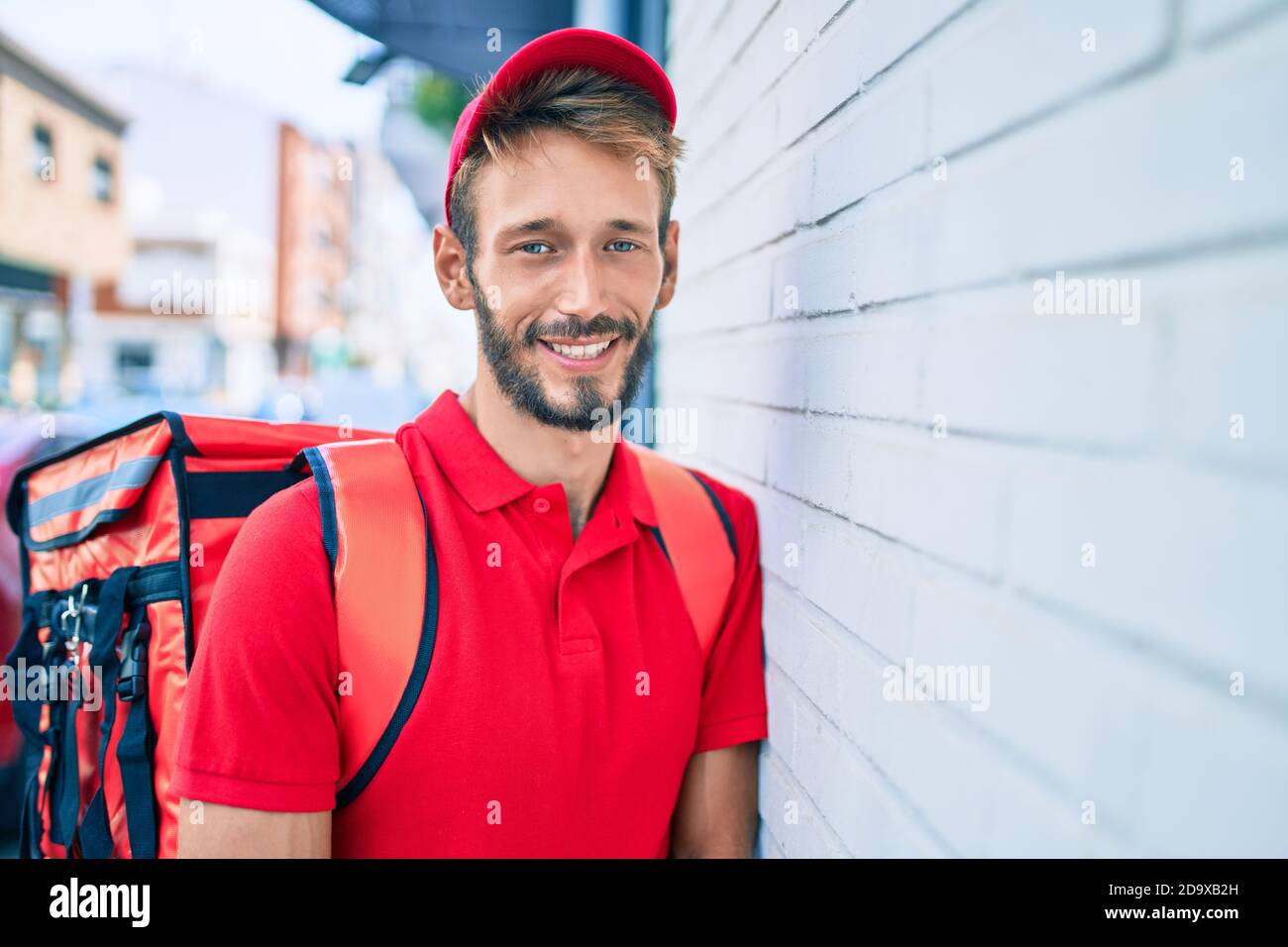 Caucasian delivery man wearing red uniform and delivery backpack smilly ...