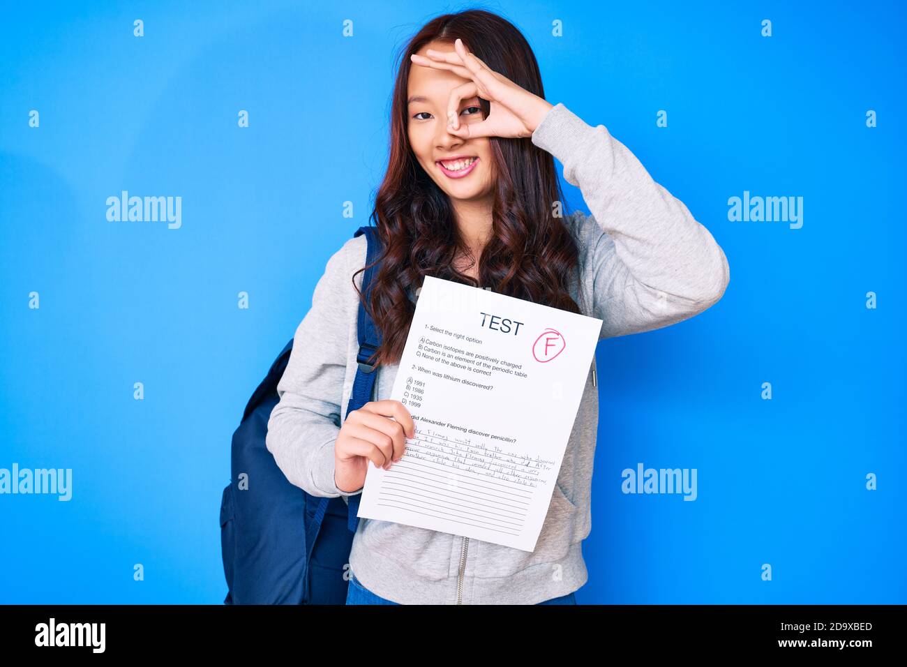 Young beautiful chinese girl showing a failed exam smiling happy doing ...
