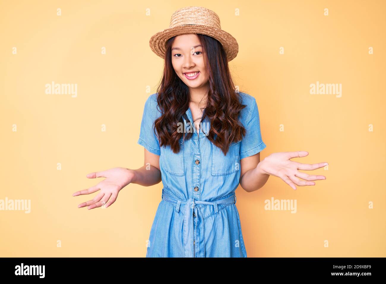Young beautiful chinese girl wearing summer hat clueless and confused ...