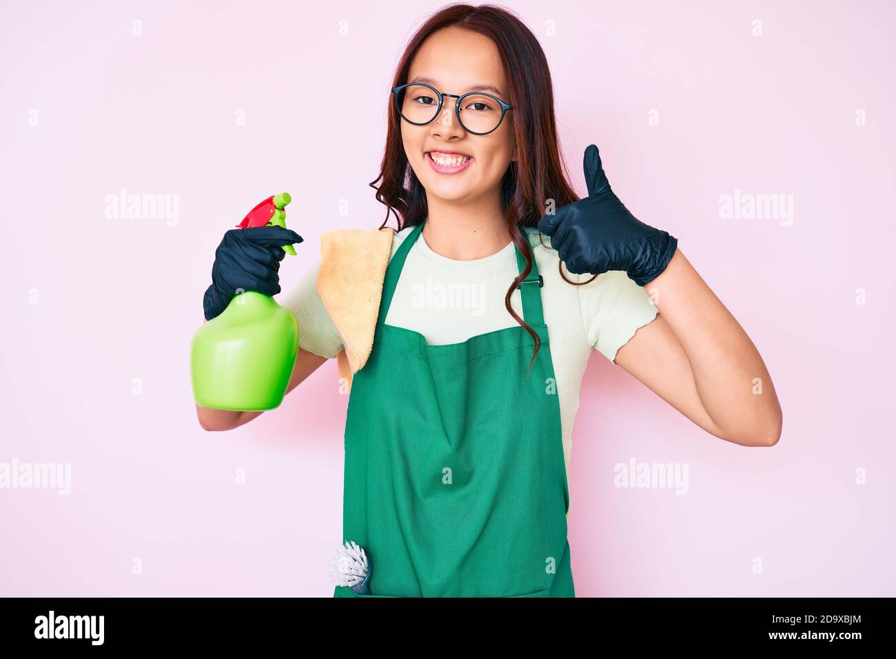 Young beautiful chinese girl wearing apron holding sprayer smiling ...