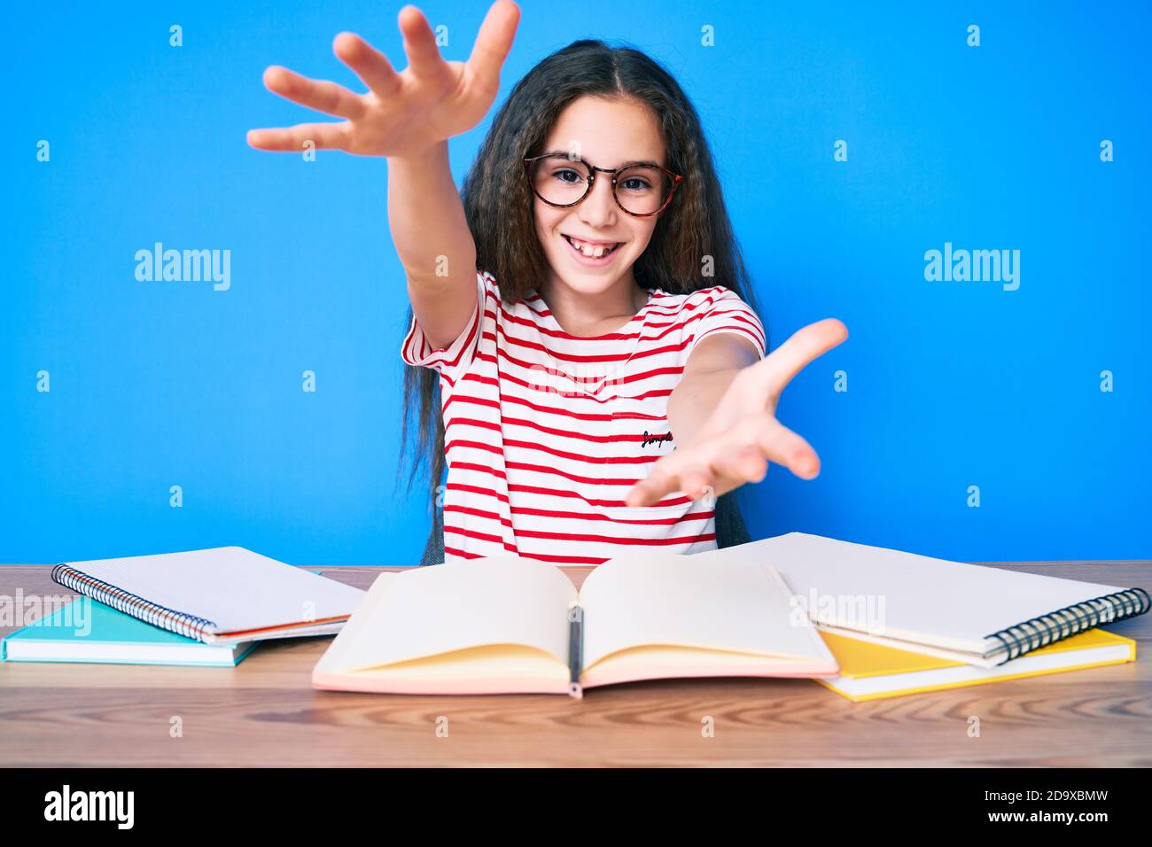 Cute hispanic child girl studying for school exam sitting on the table ...